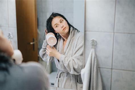 Woman Drying Her Hair With A Dryer In A Bathroom Mirror Reflection