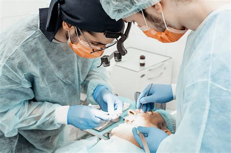 치과 의사는 수술 임플란트 배치를 수행합니다 실제 작동 치아 추출 임플란트 전문 유니폼과 치과 의사의 장비 의료 는 의사 작업장 장착 치과 거울에 대한 스톡 사진 및 기타