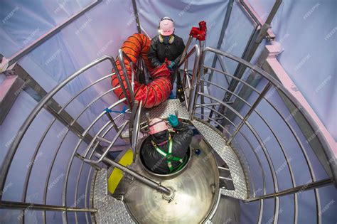 상위 뷰 남성 작업자는 탱크 스테인리스 화학 영역 밀폐 공간 안전 송풍기 신선한 공기로 계단을 올라 프리미엄 사진