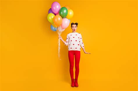 많은 화려한 공기 풍선을 들고 재미 있는 여자의 전체 길이 사진 예기치 않은 깜짝 착용 마음 패턴 스웨터 빨간 바지 신발 고립