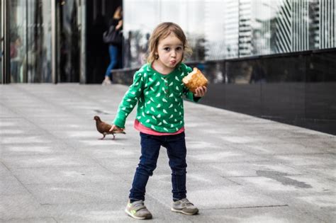 Premium Photo Portrait Of Cute Girl Eating Bread While Standing On