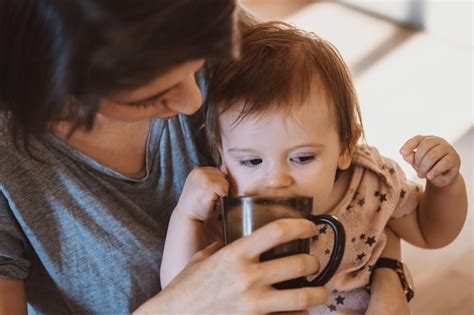 Retrato aproximado da jovem mãe e filha tomando café da manhã saudável na cozinha linda Foto