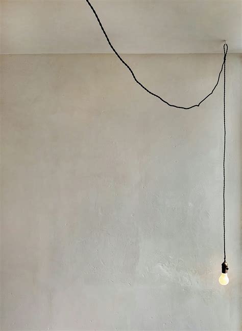 A Room With A White Wall And A Black String Hanging From The Ceiling