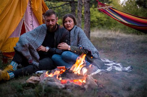 아름 다운 커플 앉아 캠프 파이어 주위에 캠핑 텐트와 배경에 남자 막대기로 화재 제스처 건강한 생활방식에 대한 스톡 사진 및 기타 이미지 Istock