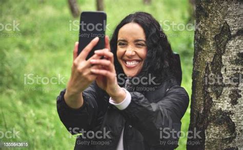 하이킹 을하는 동안 숲에 홀로 서서 휴대 전화로 셀카를 찍는 매력적인 젊은 여성의 샷 20 29세에 대한 스톡 사진 및 기타 이미지 20 29세 40 44세