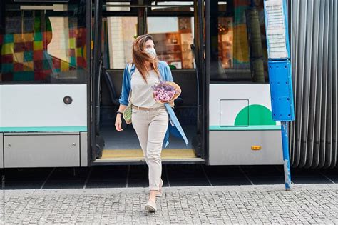 Woman In A Face Mask Getting Off A City Bus By Stocksy Contributor