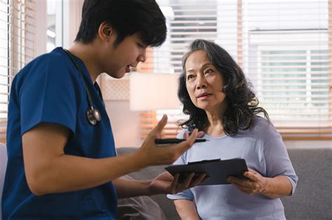 건강 방문자가 집에서 소파에 앉아있는 아픈 노인 여성을 검사하고 있습니다 가정 건강 관리 서비스 개념입니다 2명에 대한 스톡