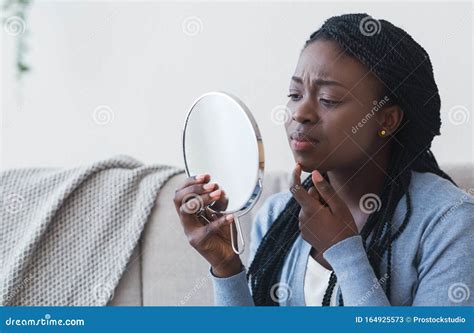 African Girl Looking In Round Mirror And Touching Her Chin Stock Image