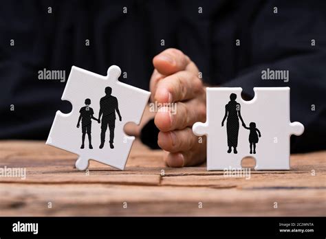 Man Dividing Two Jigsaw Puzzle Pieces With Hand Showing Divorce Concept Over Textured Wooden