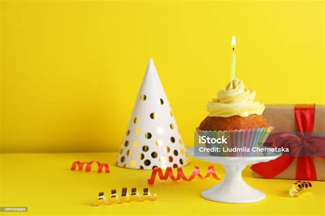 선물 상자 근처에 촛불이있는 맛있는 생일 컵 케이크와 노란색 배경의 파티 모자 텍스트를위한 공간 0명에 대한 스톡 사진 및 기타