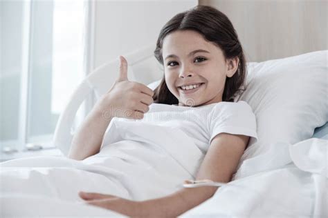 Brave Little Patient Smiling And Thumbing Up In Hospital Bed Stock