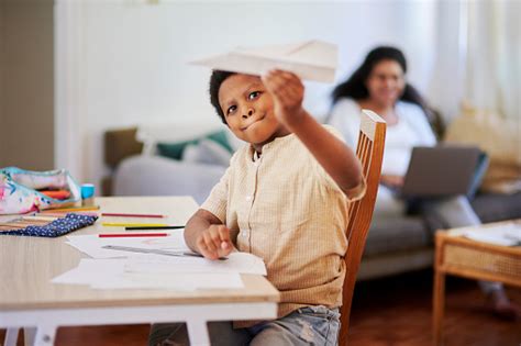 비행기 종이 아이가 집에 있는 테이블에서 재미있게 놀고 거실에서 예술과 공예로 놀고 휴식을 취합니다 창의적이고 어린 시절과 행복한 소년 종이 접기 제트기 비행 여행 게임 및