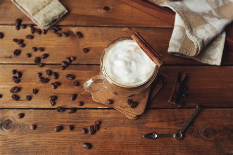 커피가 있는 유리 투명 커피 컵과 거친 나무 테이블에 계피와 우유 거품이 겹치며 흩어져 있는 커피 콩 최고 전망 0명에 대한 스톡 사진 및 기타 이미지 Istock