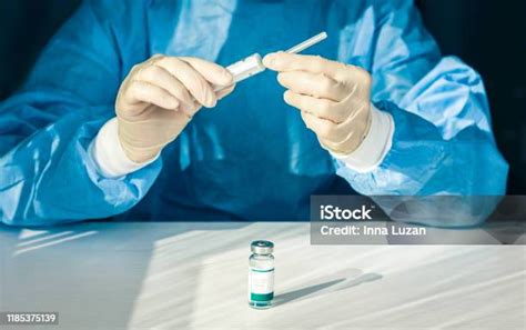 파란 수술 가운과 마스크를 입은 의사가 주사를 위한 약물이 있는 의료용 주사기와 병을 손에 들고 있습니다 건강관리와 의술에 대한 스톡 사진 및 기타 이미지 Istock