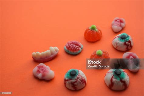 할로윈 눈 두뇌 두개골 송곳니가있는 치아 밝은 주황색 배경의 오른쪽 아래 모서리에있는 호박의 형태로 젤리 사탕 복사 공간 0명에