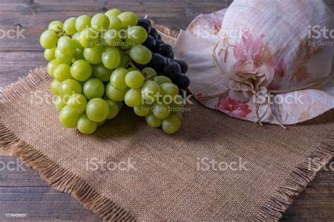 녹색과 검은 포도의 잘 익은 육즙 수확의 클러스터와 여성의 모자는 나무 테이블에 누워 건강한 생활방식에 대한 스톡 사진 및 기타