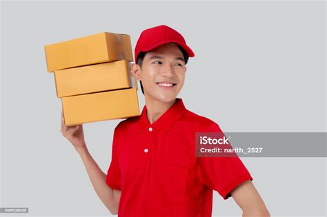 유니폼 빨간색과 모자를 쓴 젊은 아시아 남자는 상자 스택을 격리 된 흰색 배경 직원화물 또는 패키지 택배 및 배달 운송 및 서비스 물류 및화물을 들고 있습니다 고용과 노동에