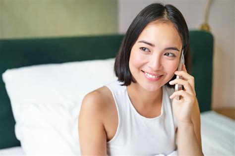 Lächelndes Koreanisches Mädchen Im Bett Spricht Auf Dem Handy Und