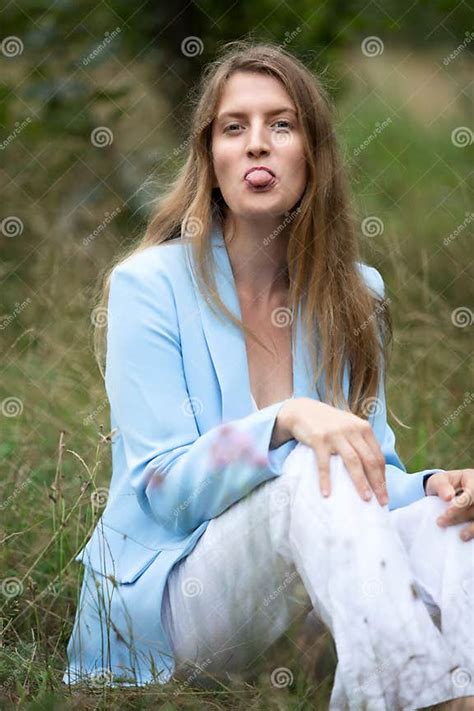 Joven Sentada En El Pasto Y Sacando La Lengua Foto De Archivo Imagen