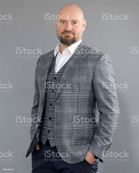 회색 재킷 조끼 흰색 셔츠를 입은 기쁜 수염을 가진 중년 사업가의 초상화는 주머니에 손을 대고 서 있습니다 재킷에 대한 스톡