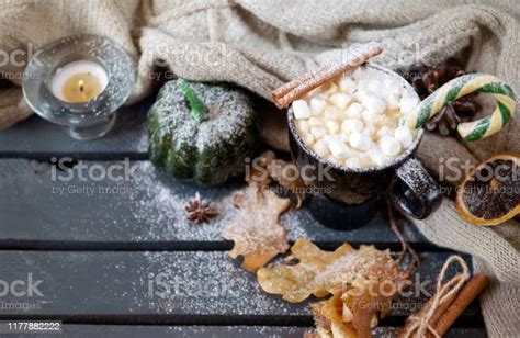 뜨거운 커피 잔 마시멜로와 사탕 계피 작은 녹색 호박 촛불 회색 나무 배경에 니트 스웨터 옆에 건조 한 가을 단풍을 많이 초콜릿
