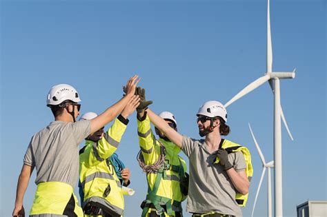 남성 엔지니어 그룹이 서서 풍력 터빈 농장에서 함께 손을 잡고 안전 유니폼과 헬멧을 착용합니다 팀 엔지니어 작업이 완료되었습니다 성공적인 작업 20 24세에 대한 스톡 사진