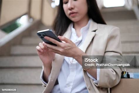 해고된 여성 노동자는 개인 물건 상자를 들고 건물 계단에 앉아 전화를 사용하고 있다 실업자 개념 30 34세에 대한 스톡 사진