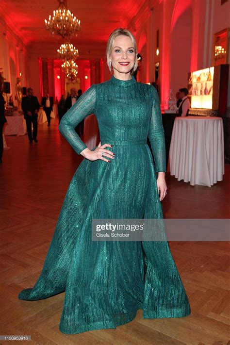 A Woman In A Green Dress Poses For The Camera On A Wooden Floor At An Event