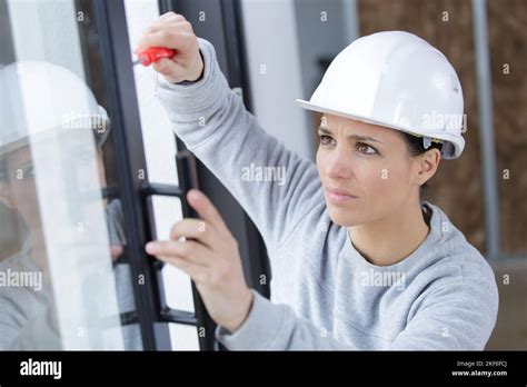Female Worker Using Screwdriver Working On Pvc Window Frame Stock Photo