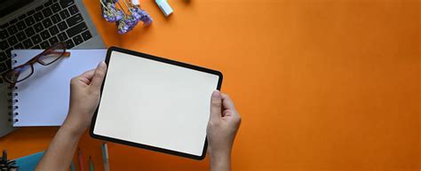 컴퓨터 노트북 안경 마커 펜 연필 노트북과 화려한 작업 책상에 넣어 꽃 위에 흰색 빈 화면 컴퓨터 태블릿을 들고 창조적 인 여성의 손의 상단보기 이미지 0명에 대한 스톡