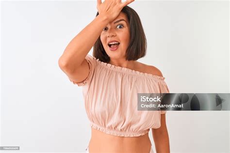 캐주얼 한 티셔츠를 입고 고립 된 흰색 배경 위에 서있는 젊은 아름다운 여성은 실수로 머리에 손을 대고 놀랐습니다 오류를