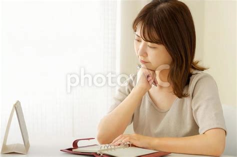 手帳を見ながら予定を考える若い女性 No 27108461｜写真素材なら「写真ac」無料（フリー）ダウンロードok