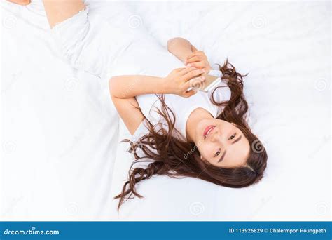 Young Happy Asian Woman Laying On Her Bed Using Her Smartphone T Stock