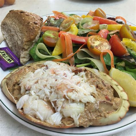 A White Plate Topped With Food Next To A Salad