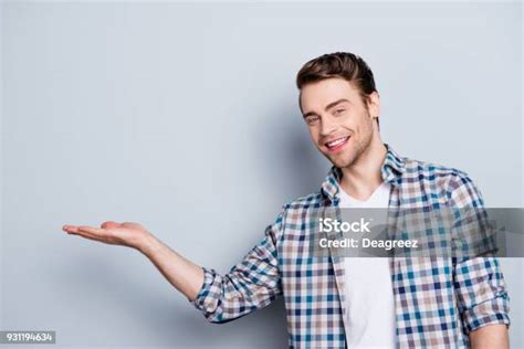 제시 하는 새로운 제품 시동 회색 배경 위에 서 서 그의 손바닥에 복사 공간을 보여주는 성공 쾌활 한 귀여운 전문 젊은 남자의 초상화를 닫습니다 고등학교에 대한 스톡 사진