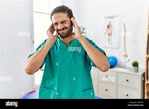 Young Physiotherapist Working At Pain Recovery Clinic Covering Ears