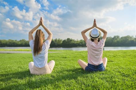 Premium Photo Two Women Sitting In Lotus Position On Green Grass