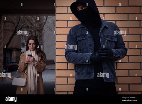 Criminal With Knife Hiding Behind Wall And Waiting For Victim Near