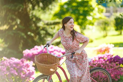긴 핑크 꽃 드레스에서 유행 젊은 여자의 초상화 빈티지 자전거 구매에 대 한 바구니와 꽃 배경 야외에 승마를 중지 합니다 봄 또는 여름 공원에서 예쁜 여성 오락 시간 거리에