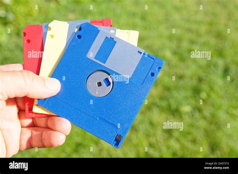 Vintage Colored Floppy Disks In A Hand On Green Grass Lawn Background Old Technologies