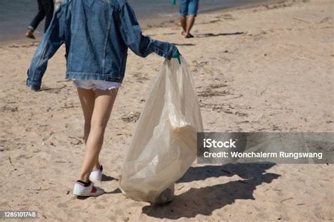 환경과 생태를 보호하기 위해 큰 비닐 봉지에 플라스틱 쓰레기와 쓰레기를 집어 들고 여름에 는 젊은이와 십대 운동가와 지역 사회의 사람들이 더러운 해변을 청소하고 있습니다