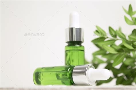 Green Glass Dropper Bottles On White Background With Leaves Stock Photo