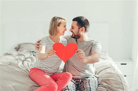 행복한 강한 결혼 빨간 종이 마음을 들고 사랑에 행복한 재미있는 부부 이성애자 가족 남자와 여자는 집에서 포옹에서 침실에 침대에