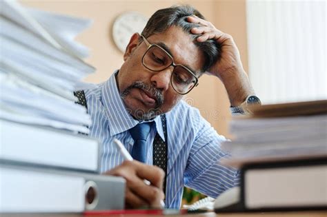 Concentrating On Work At Office Desk With Stacked Papers Stock Image