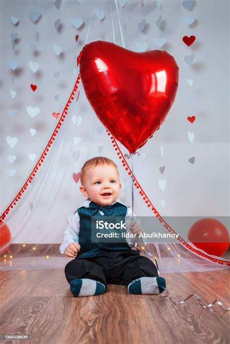발렌타인 데이 행복한 어린 아기 소년은 마음과 미소의 형태로 빨간 공을 들고 앉아 배경에는 하트로 장식된 흰색 배경이 있습니다 6 11 개월에 대한 스톡 사진 및 기타