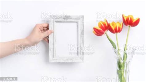 집에서 깨끗한 벽에 대한 흰색 나무 테이블 배경에 사진 프레임 장소와 유리 꽃병에 튤립 꽃 닫다 어머니의 날 장식 개념 0명에