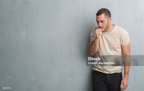 기분이 불쾌 하 고 감기 나 기관지염에 대 한 증상으로 기침 하는 회색 그런 지 벽에 젊은 백인 남자 의료 개념입니다 감기와