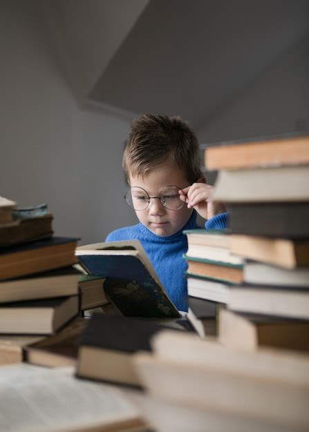 Menino de cinco anos de óculos lendo um livro uma pilha de livros