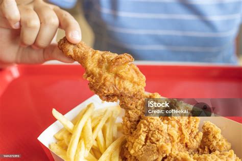 감자 스틱 프렌치 프라이와 함께 프라이드 치킨을 먹는 클로즈업 사람들은 미국식 지방 음식을 먹습니다 닭고기 튀김에 대한 스톡