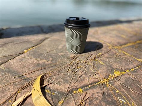 Xícara de café de plástico no chão de cimento no fundo brilhante Foto